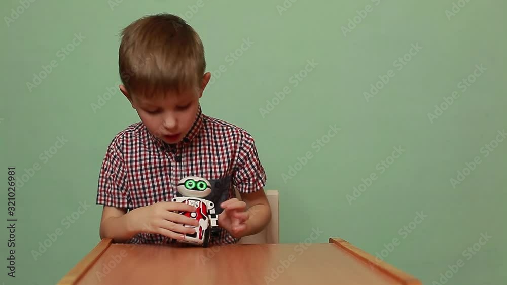 Funny boy playing with an interactive toy robot that actively rejoices ...