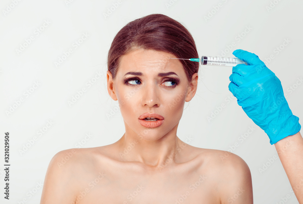 Woman looks to the syringe, is afraid of aesthetic surgery, white ...