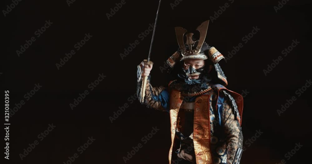 Japanese samurai in traditional armor is raising his sword and getting ...
