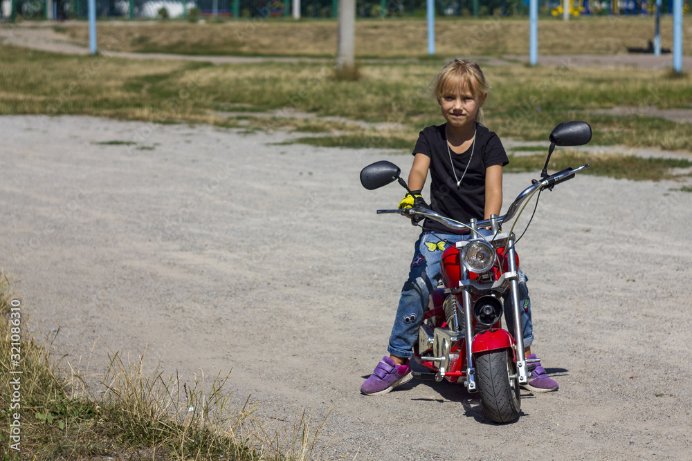 little girl child rides a children's red cool minimoto electric bike ...