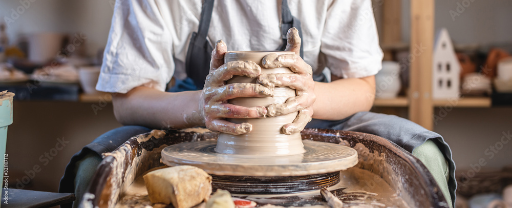 Potter working on a Potter's wheel making a vase. Young woman forming ...