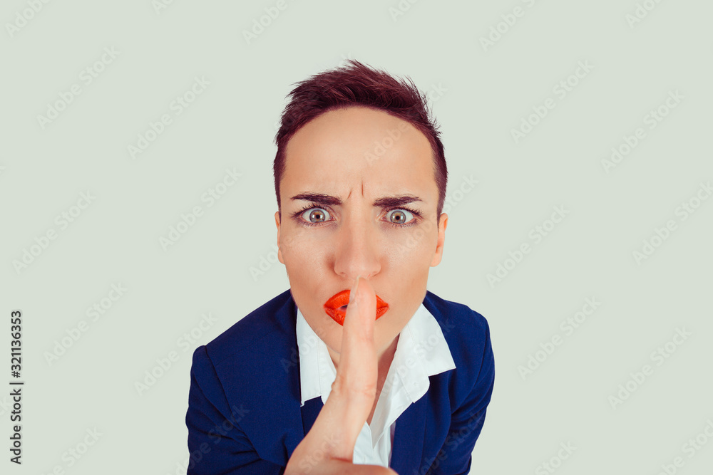 Angry woman wide eyed asking for silence or secrecy with finger on lips ...
