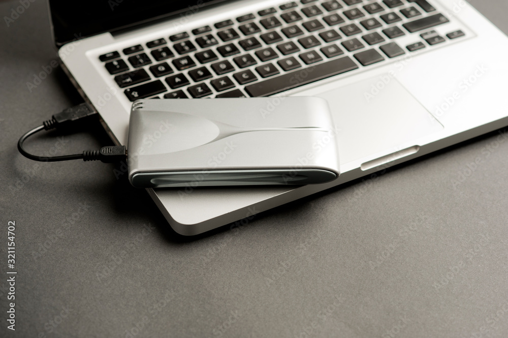 aluminum external hard drive with cable (usb) connected to laptop, on ...