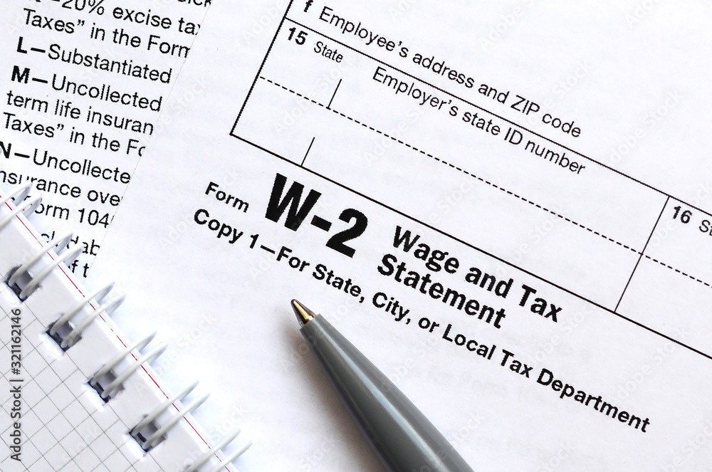 The pen and notebook on the tax form W-2 Wage and Tax Statement. The ...