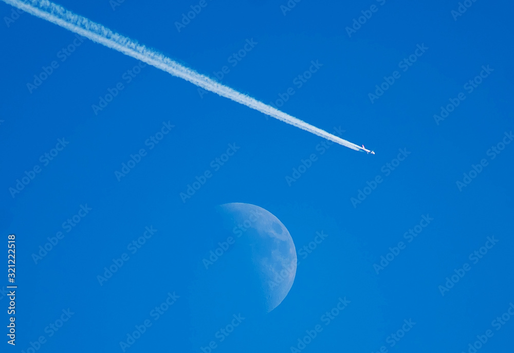 Airplane- commercial aircraft- and moon in daytime. The plane flies in ...