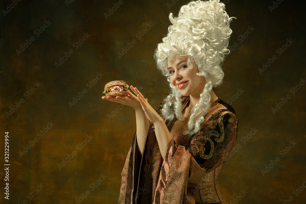 Eating burger wondered. Portrait of medieval young woman in brown ...