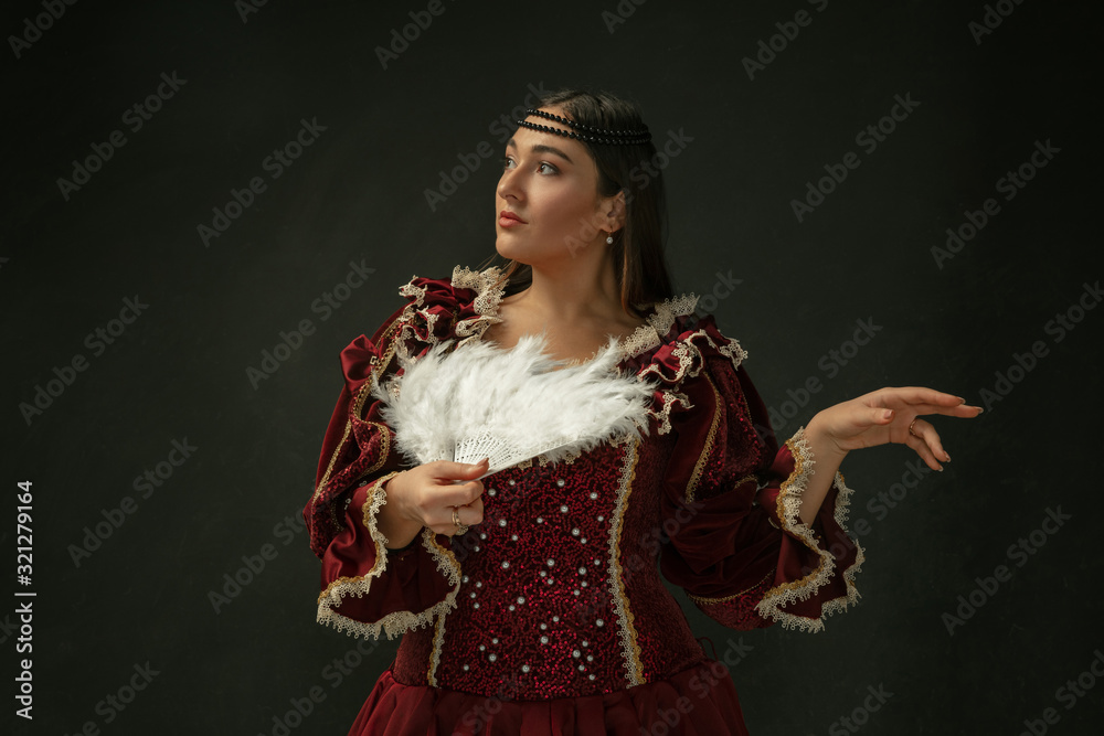 Portrait of medieval young woman in red vintage clothing posing with ...