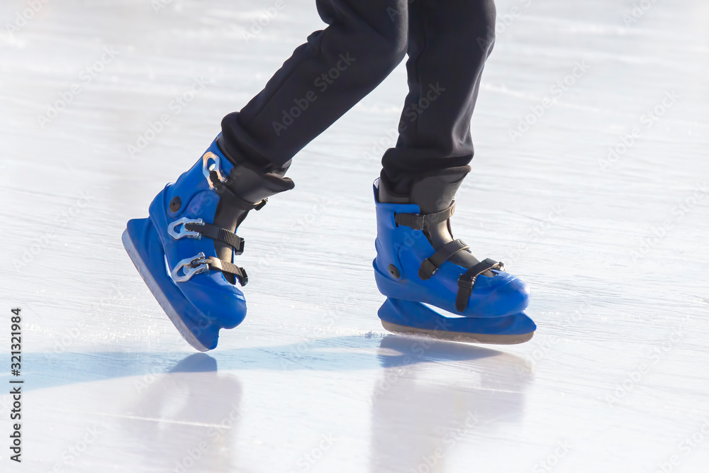 legs of a man in blue skates rides on an ice rink. hobbies and leisure ...