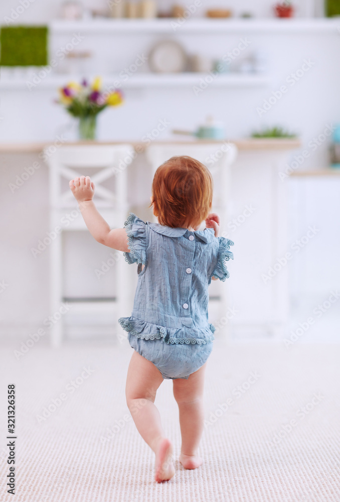 first steps of cute little baby girl in bodysuit walking away, on the ...