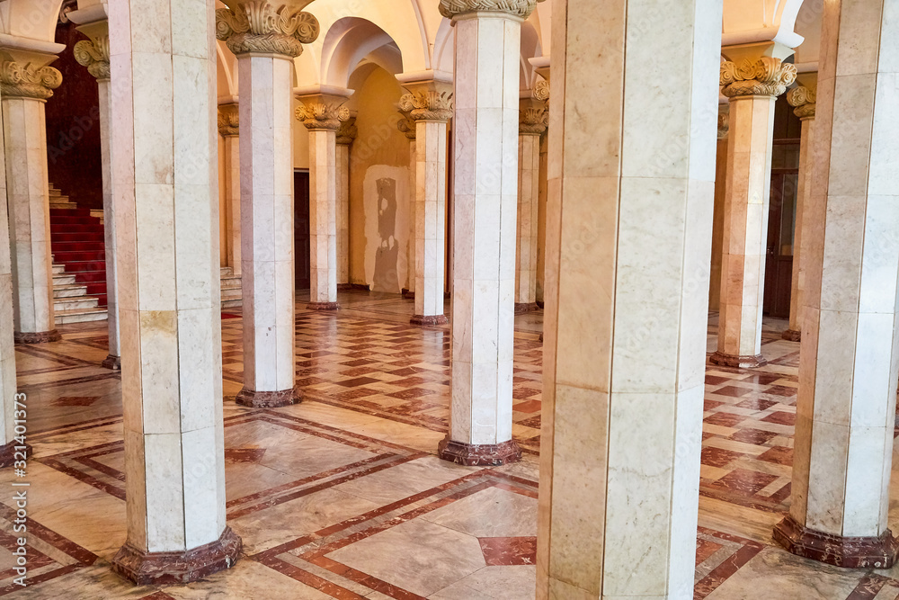 Large hall with white columns and a square checkered red tile pattern ...