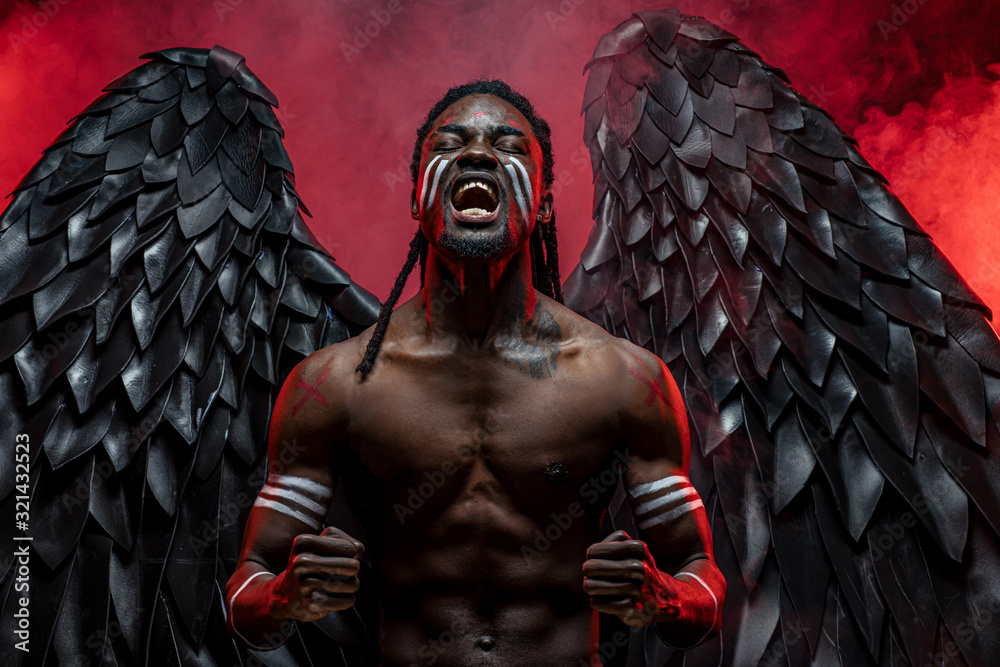 dark african angel screaming from pain isolated in red smoky space ...