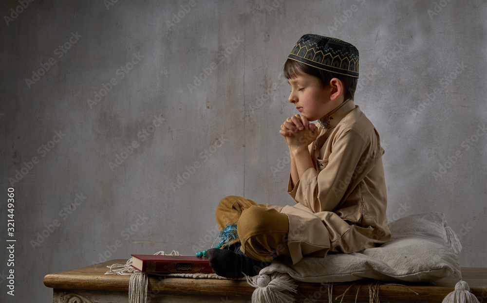 Young muslim boy in prayer cap and arabic clothes with rosary beads and ...