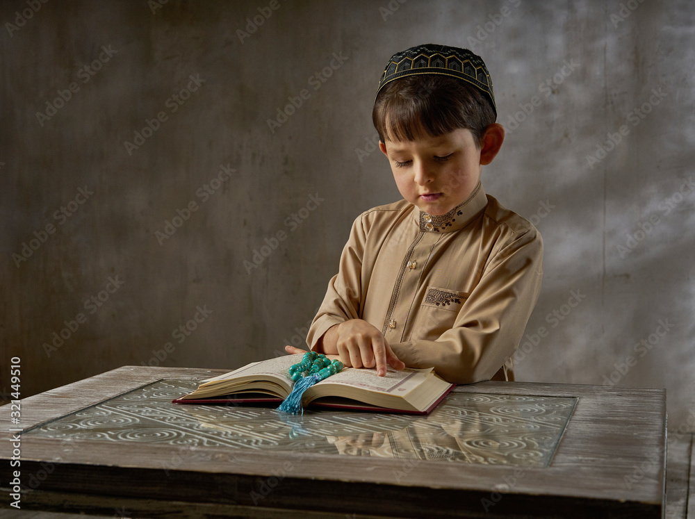 Young muslim boy in prayer cap and arabic clothes with rosary beads ...
