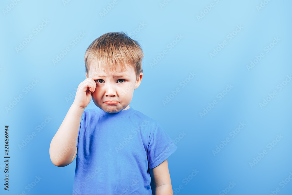 Poster Upset crying sad boy at blue background, looking at camera ...