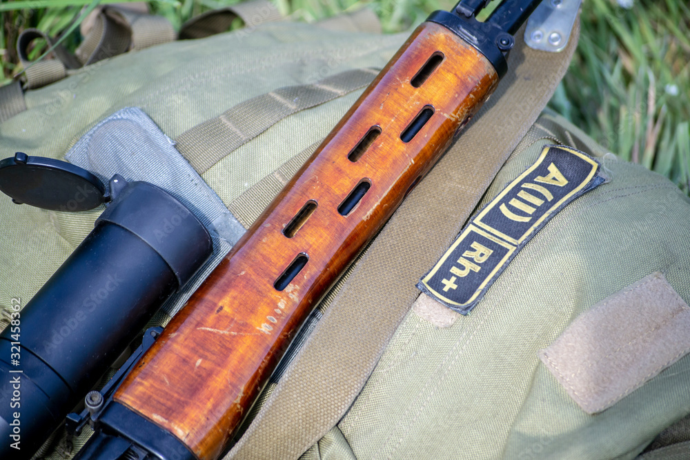 Sniper rifle with wooden fore end laying on tactical backpack with ...
