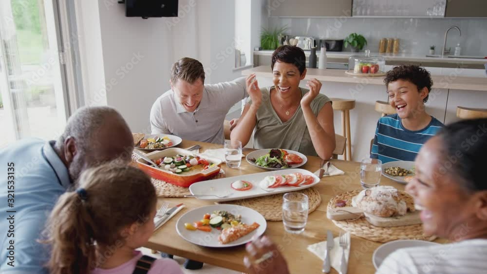 Multi-Generation Mixed Race Family Eating Meal Around Table At Home ...