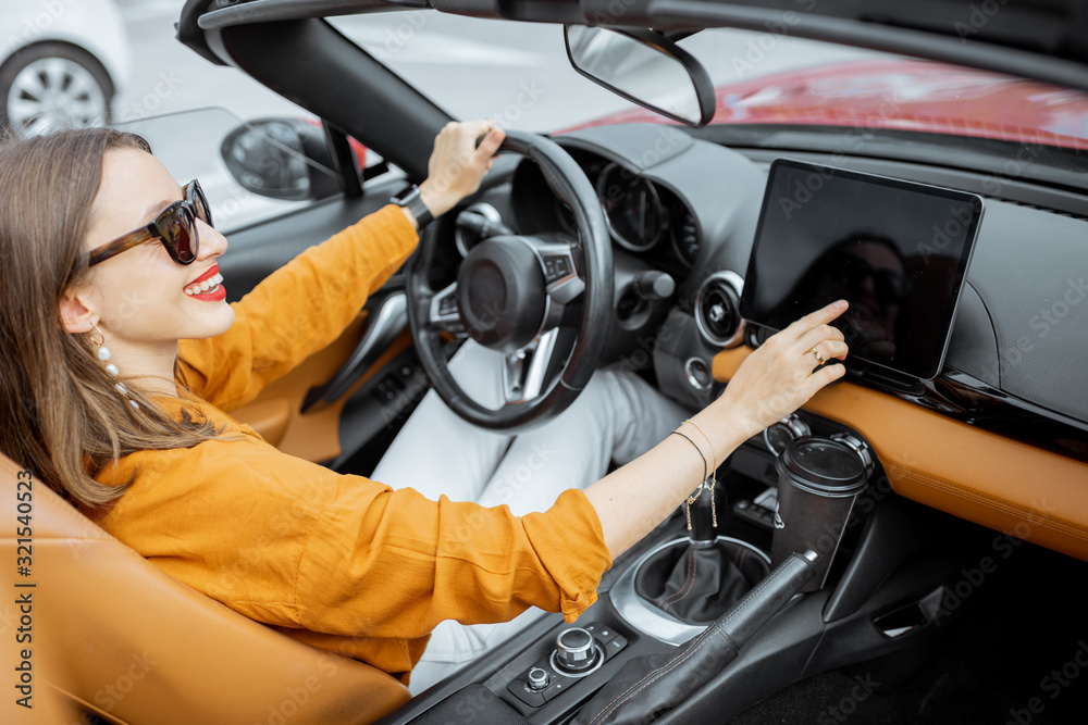 Cheerful woman controlling car with a digital dashboard while driving a ...