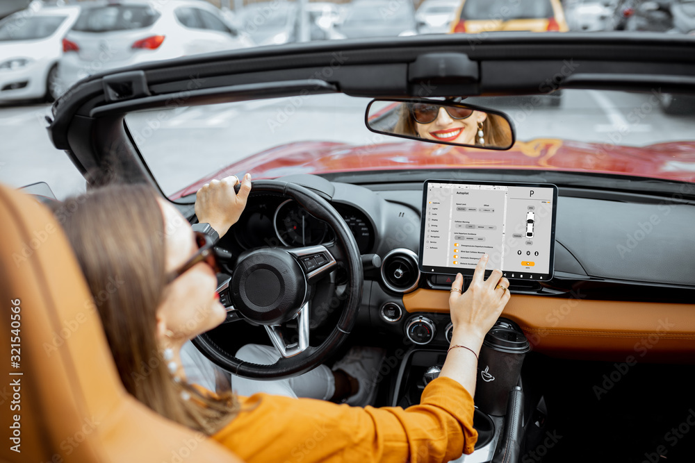 Cheerful woman controlling car with a digital dashboard, switching ...