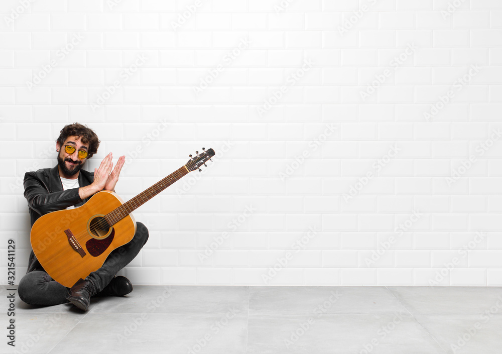 young musician man feeling happy and successful, smiling and clapping ...