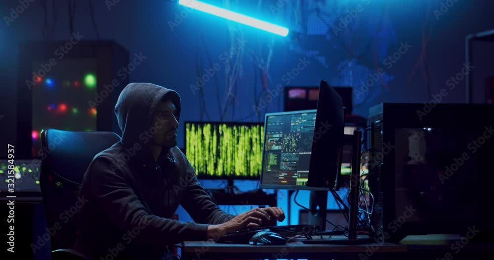Stockvideon Caucasian young hacker man in a hood working and hacking ...