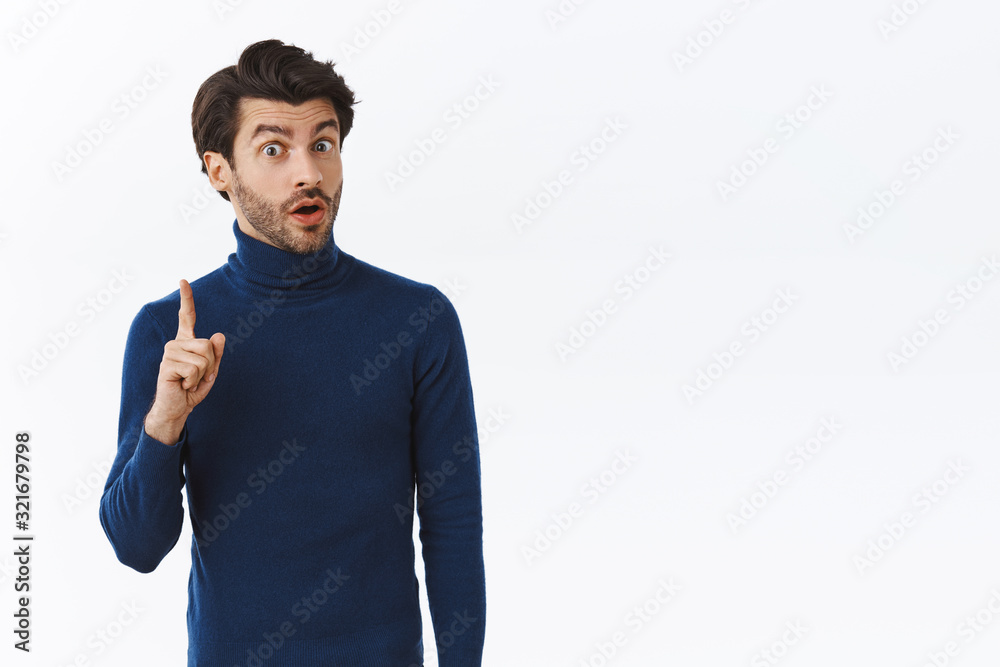 Handsome bearded man in blue high neck sweater raise one finger and ...