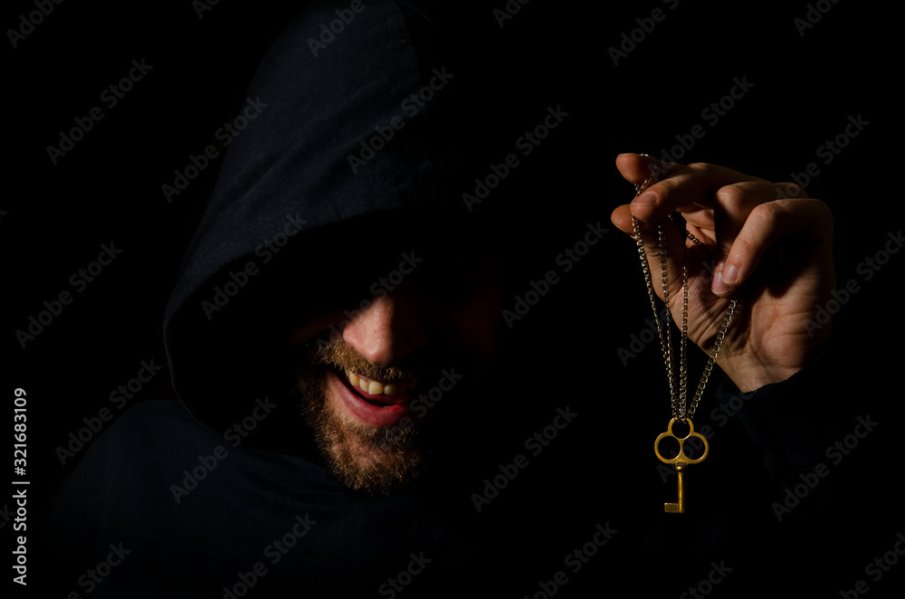 evil wizard. wicked smile. slavery. imprisonment. man in a black hood ...