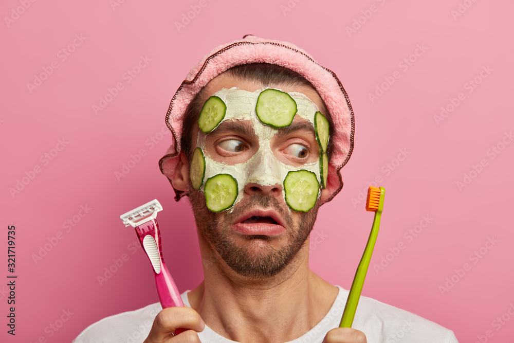 Surprised unshaven man looks with shocked expression at razor and tooth ...