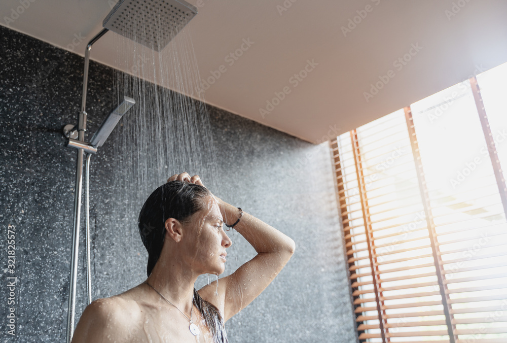 Young beautiful woman stands takes a shower in a hotel room with a ...