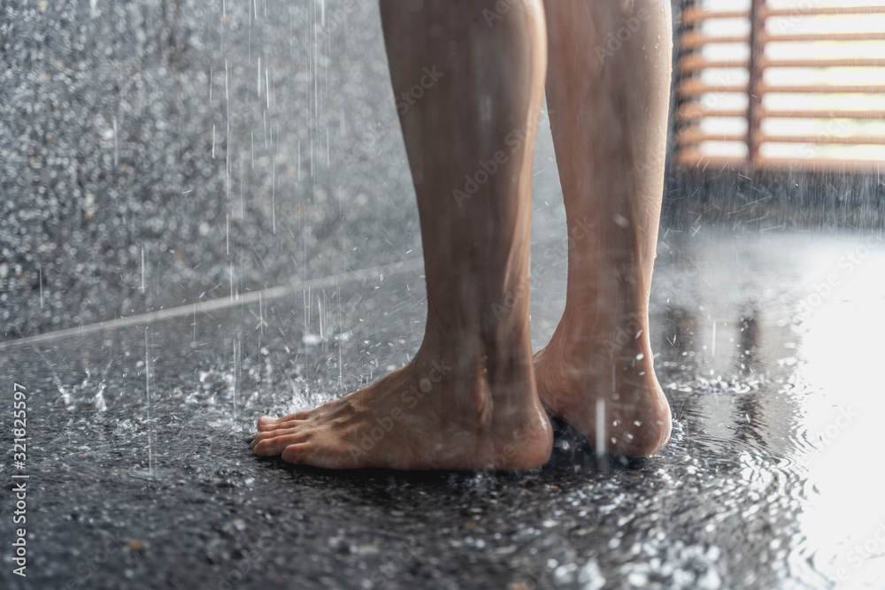 Legs of the girl standing under the shower under the stream of water ...