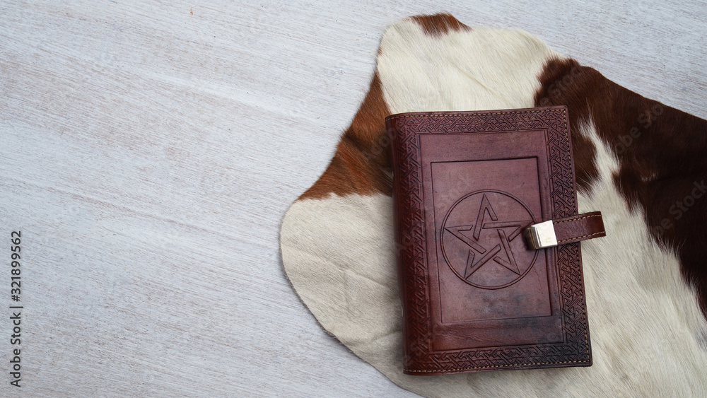 Vintage leather book with pentagram symbol laying on horse fur ...
