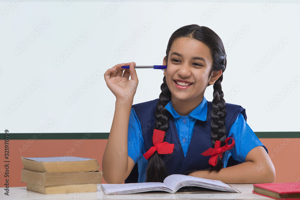Smiling school girl holding pen Stock Photo | Adobe Stock