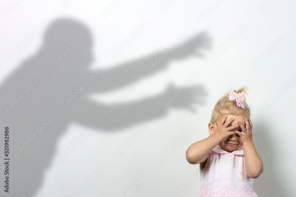 Little child covers his face with his hands on a light background with ...