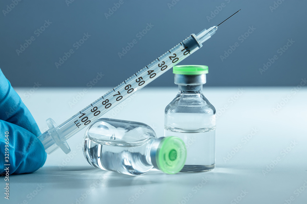 Vaccine in vial and syringe close-up on a white table gray background ...