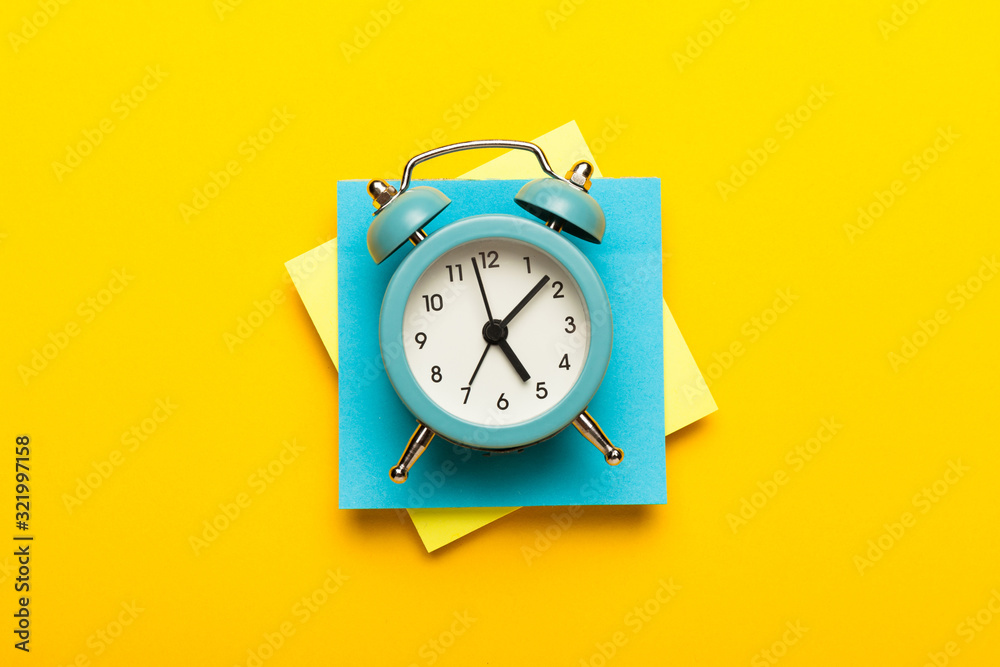 Blue analog clock on a stack of note paper. Business time distribution ...