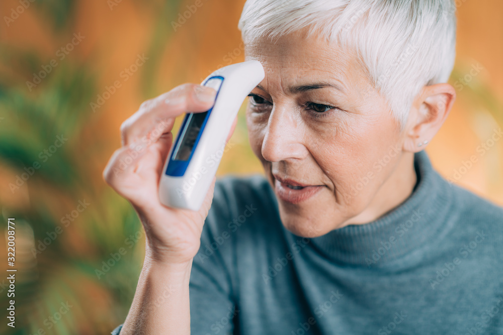 Senior Woman Measuring Body Temperature with Contactless Digital ...