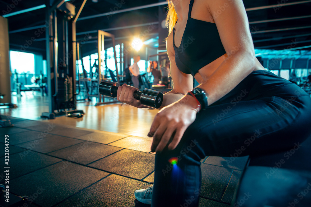 Calm. Young muscular caucasian woman practicing in gym with the weights ...