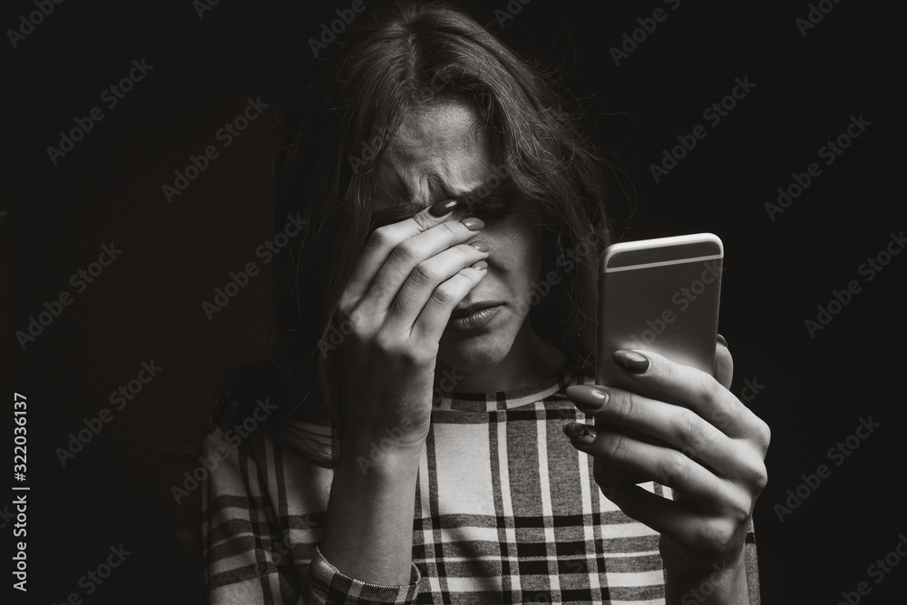 Sad teen being victim of cyber bullying online sitting on a couch in ...