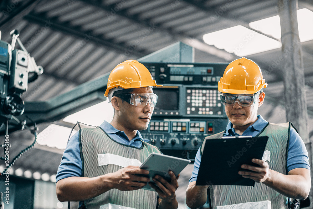 Foto de Engineer and manual worker analyzing process in industrial ...