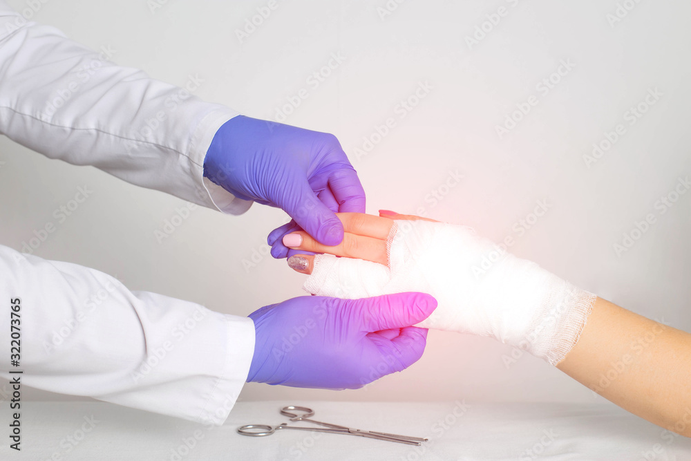 Doctor surgeon puts a splint on broken phalanges of fingers on a hand ...