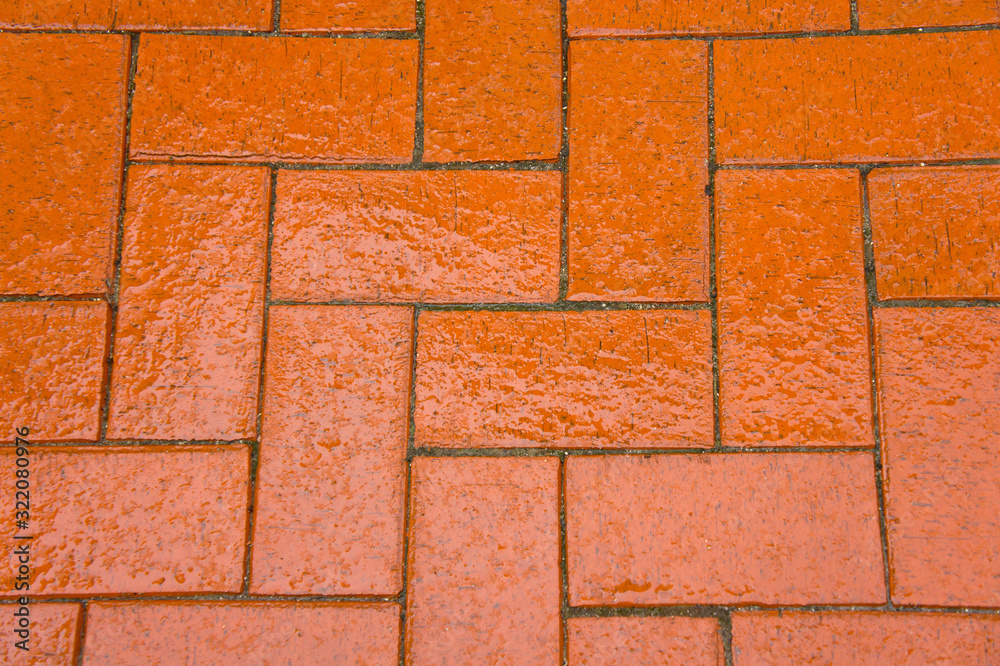 Modern paving slabs in orange, wet from rain. Background for the road ...
