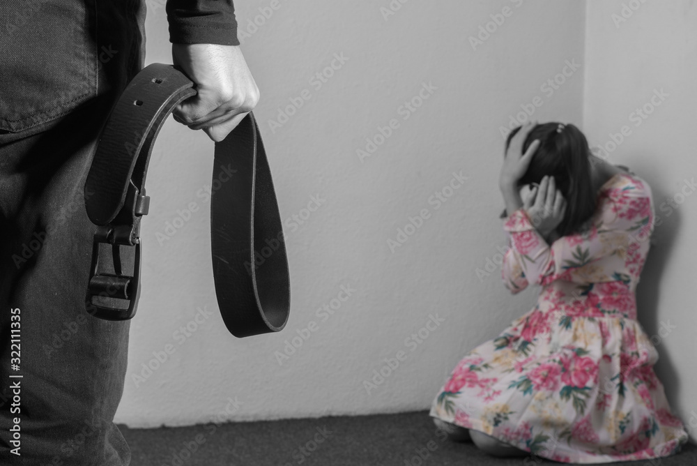 Child abuse concept. A girl in a colored dress sits in a corner, covers ...