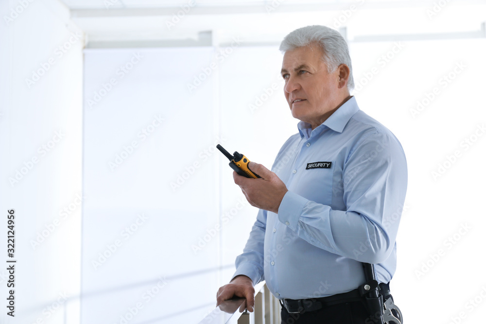 Professional security guard with portable radio set indoors Stock Photo ...