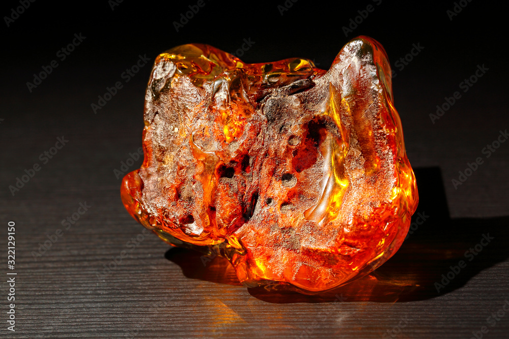 Bright translucent piece of amber with a natural crust on a black ...