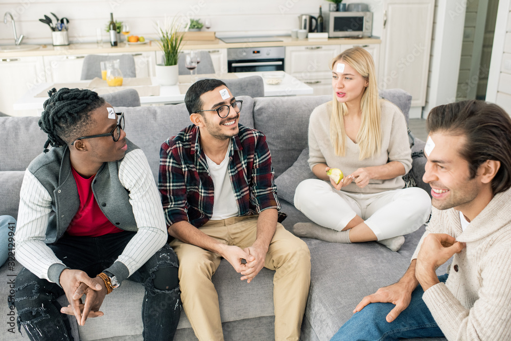 Friends sitting together on sofa im modern apartment playing Who Am I ...