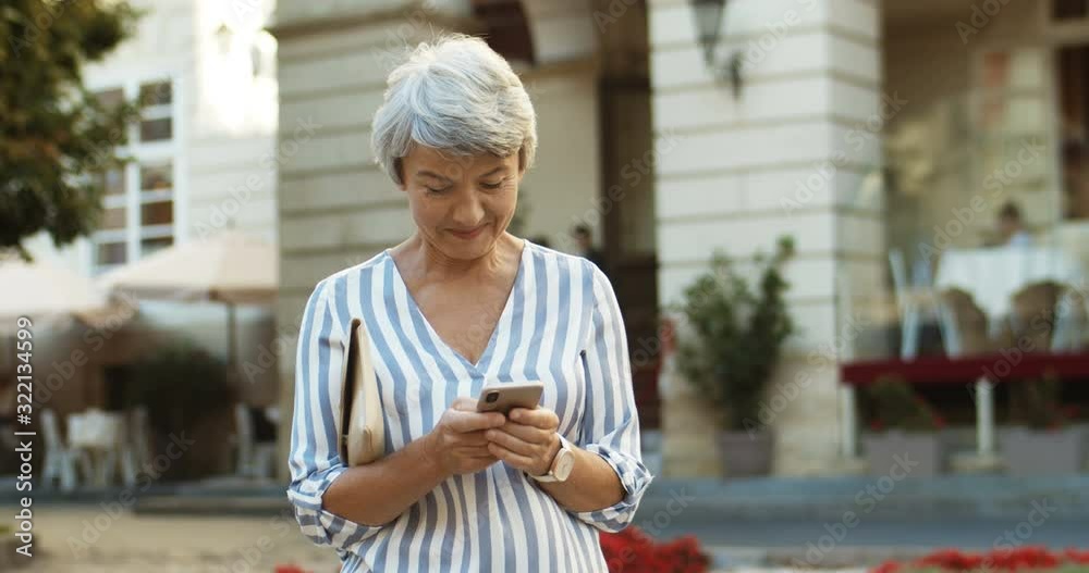 Caucasian beautiful old woman standing in center city and tapping ...