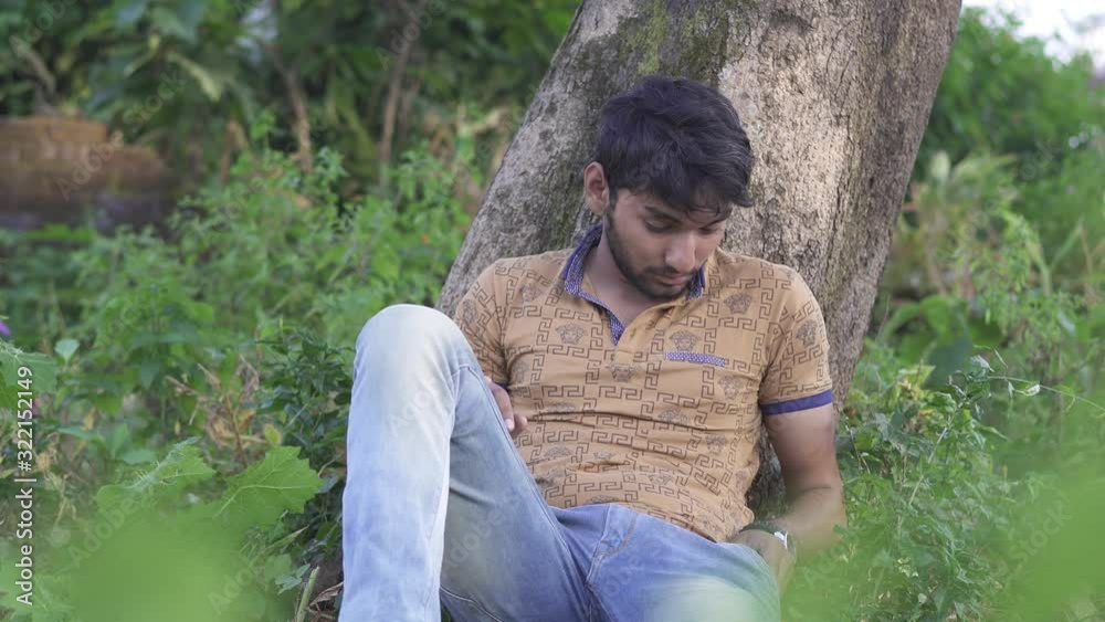 A drunk man sitting below a tree.Drunk Indian man looking tired. A ...