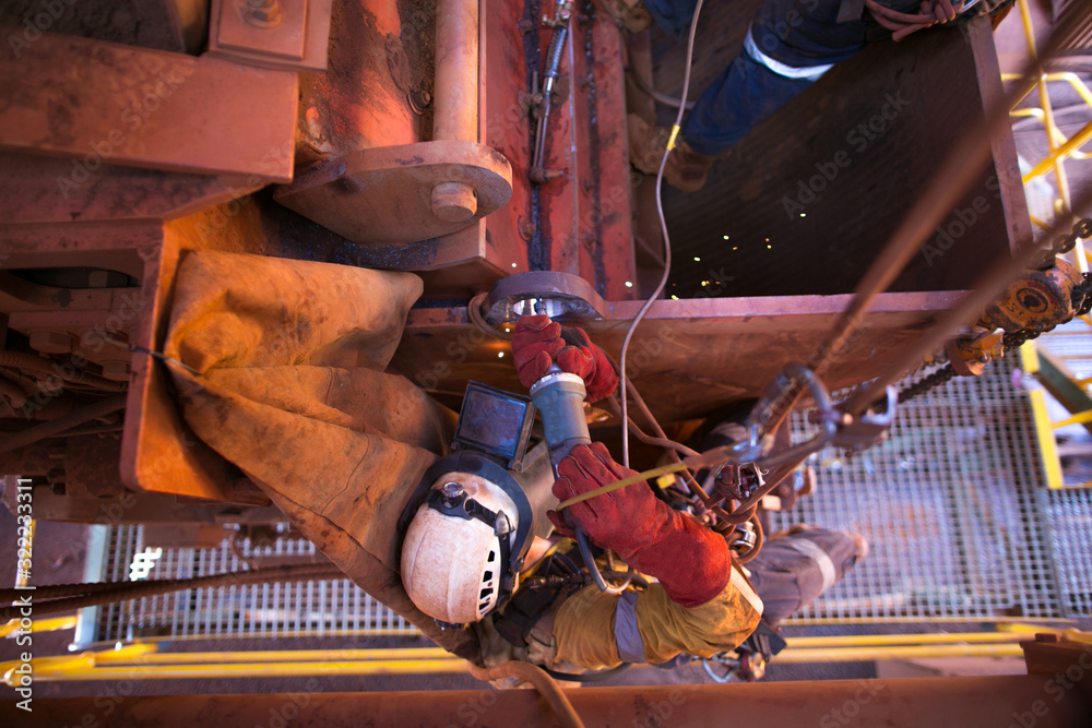 Rope access welder hanging on rope working at height in fall arrest ...
