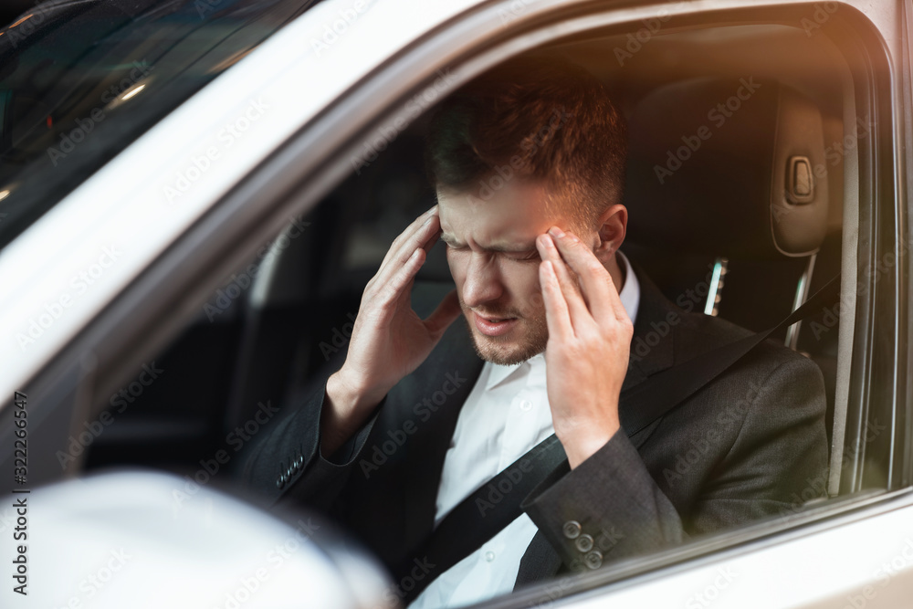young businessman suffers terrible headache while siting in his car ...