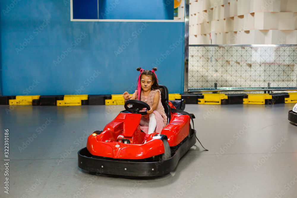 a the smiling little girl in a helmet in the go-kart on the karting ...