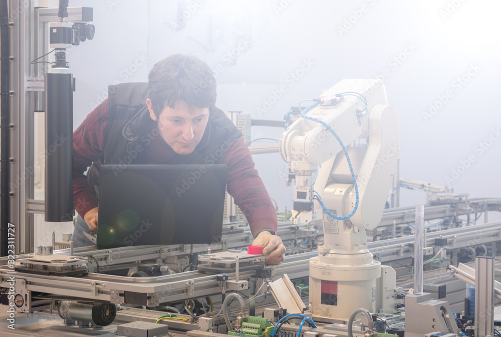 Close-up of Robot arm. Engineer is working on laptop to programming ...